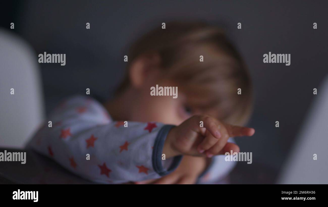 Bashful little baby boy pointing finger at laptop screen watching ...
