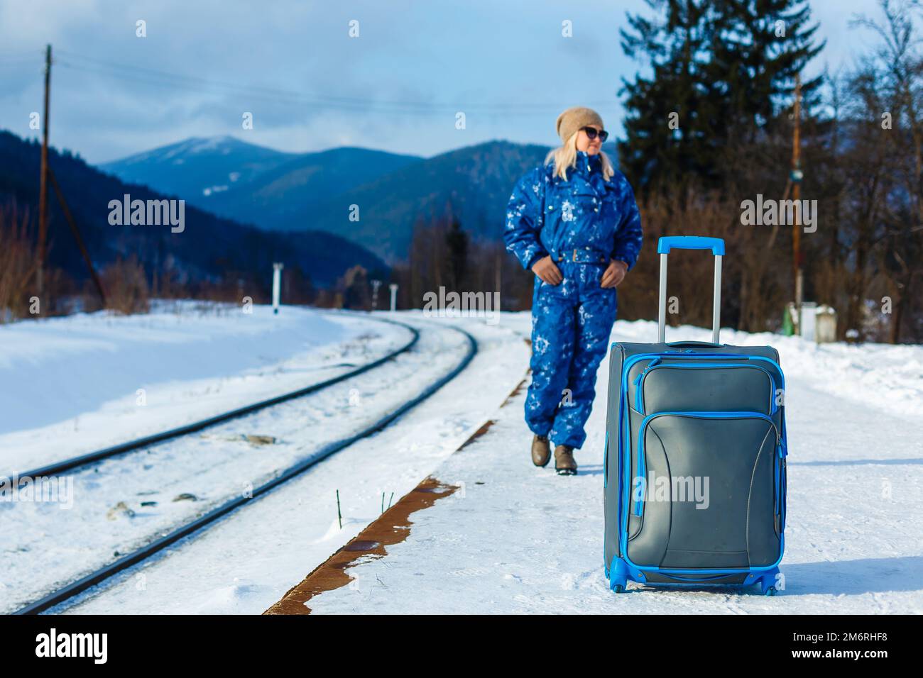 Woman pulling heavy luggage at a snow train station. Travelling by ...