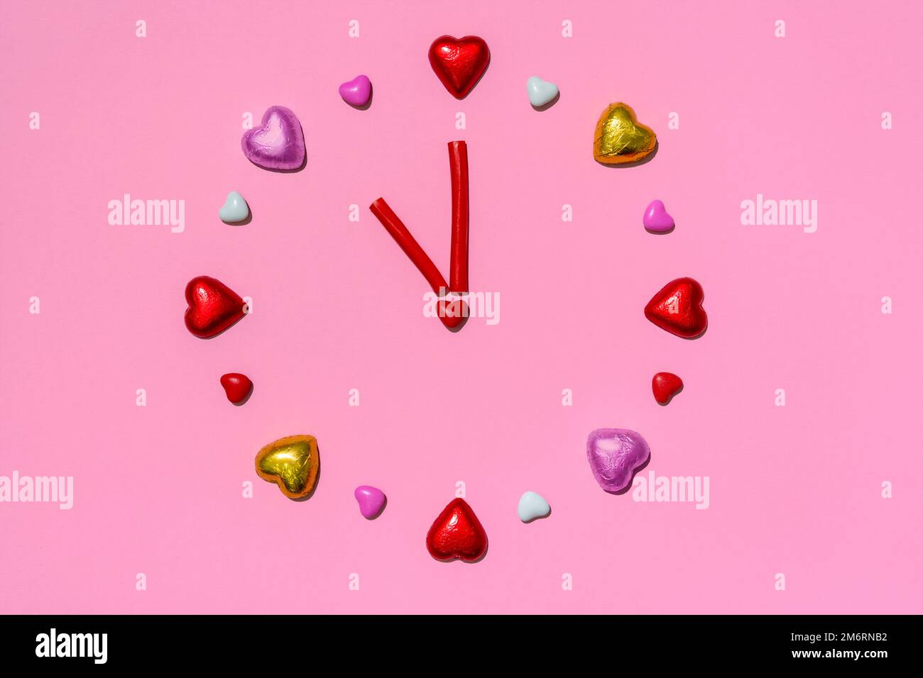 Time to love. Bigger clock sign made of chocolates hearts and candy on ...