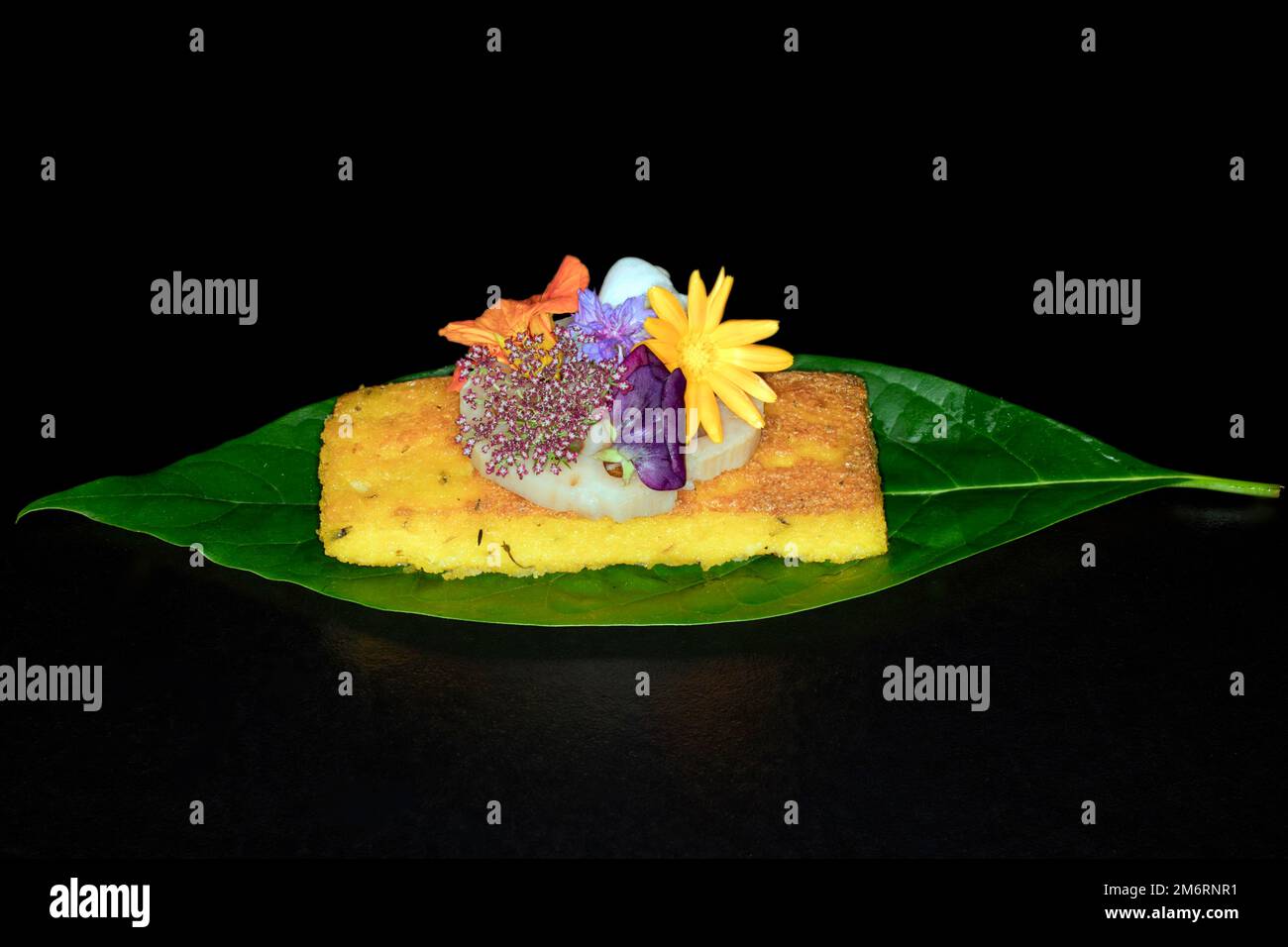 Fried polenta slice with a slice of lotus root and meadow flowers as ...