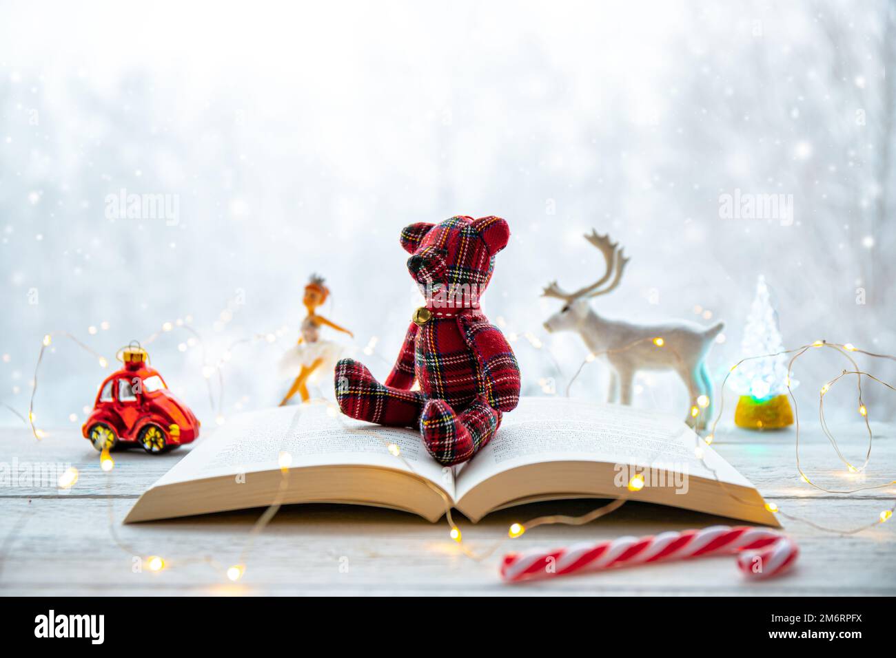 Open paper book with cute teddy bear shape figurine, fairy lights ...
