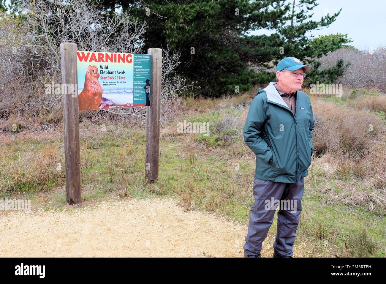 Park guide and docent in front of sign warning visitors of wild ...