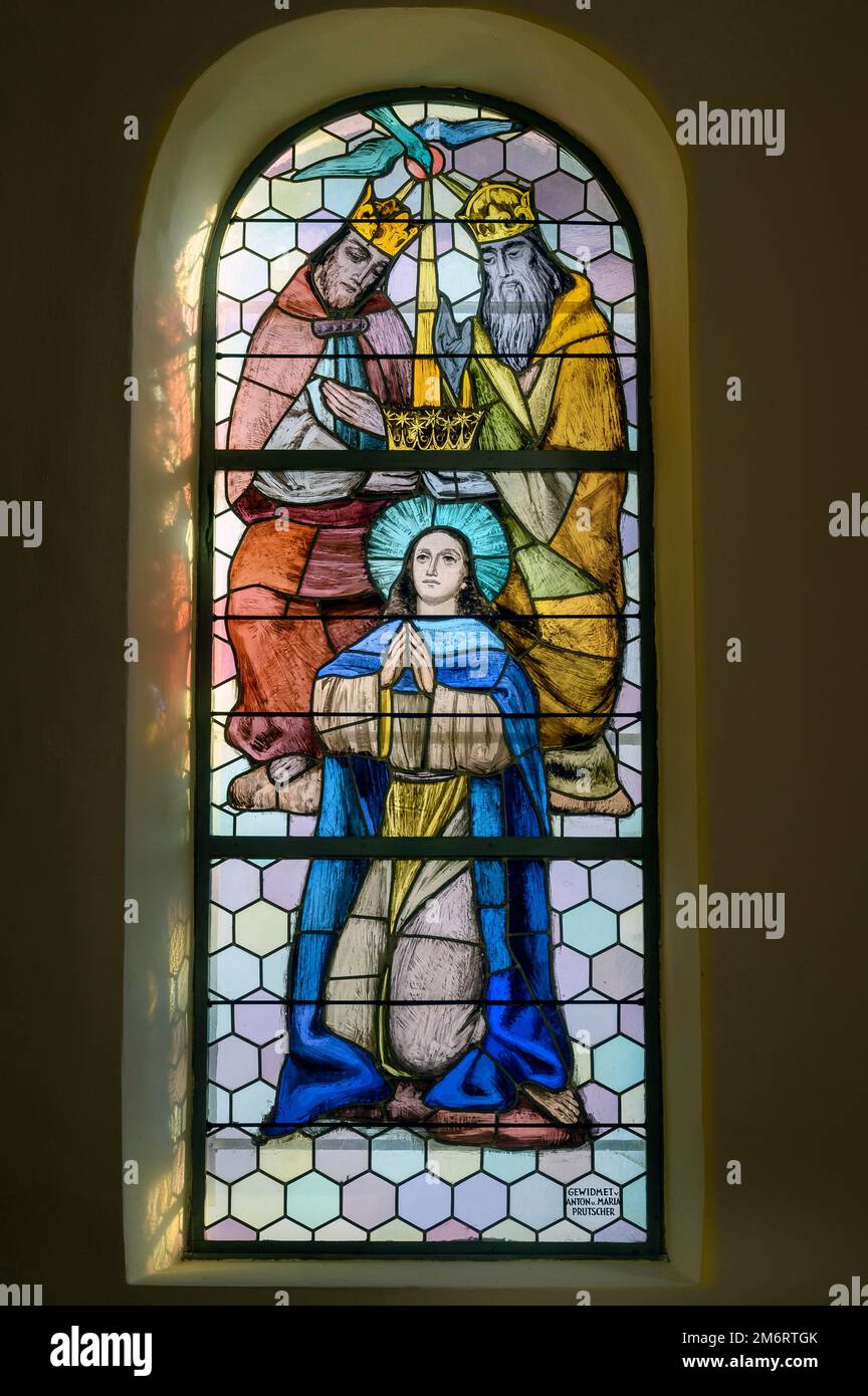Coloured stained glass window with figures of saints in the Church of ...