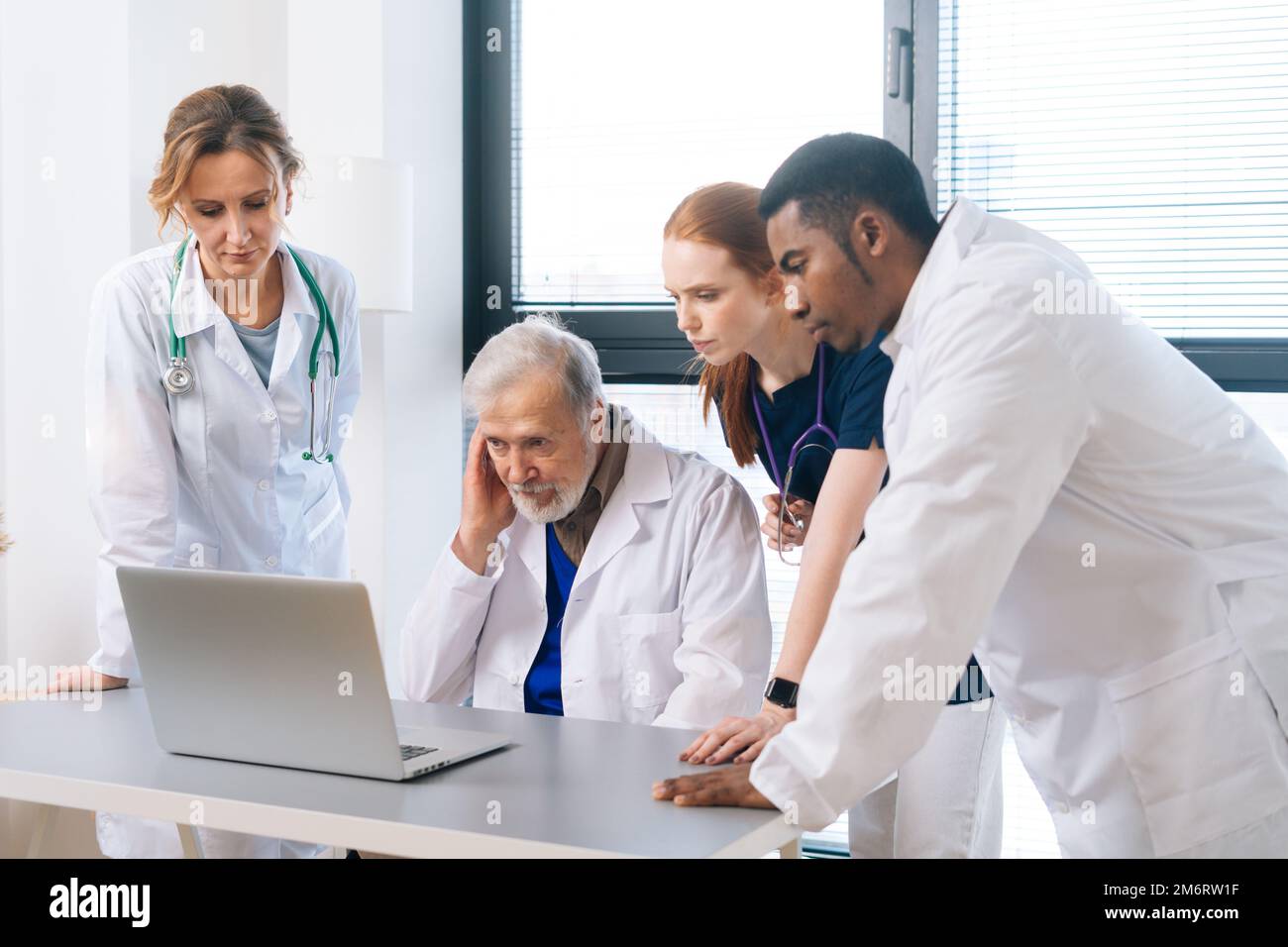 Serious medical team of multiethnic doctors talking together ...