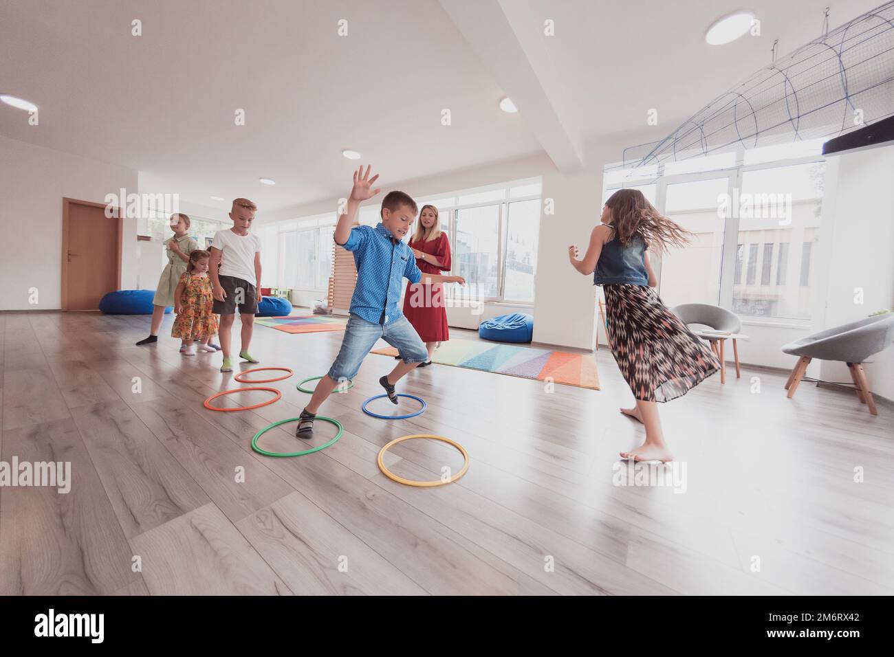 Small nursery school children with female teacher on floor indoors in ...
