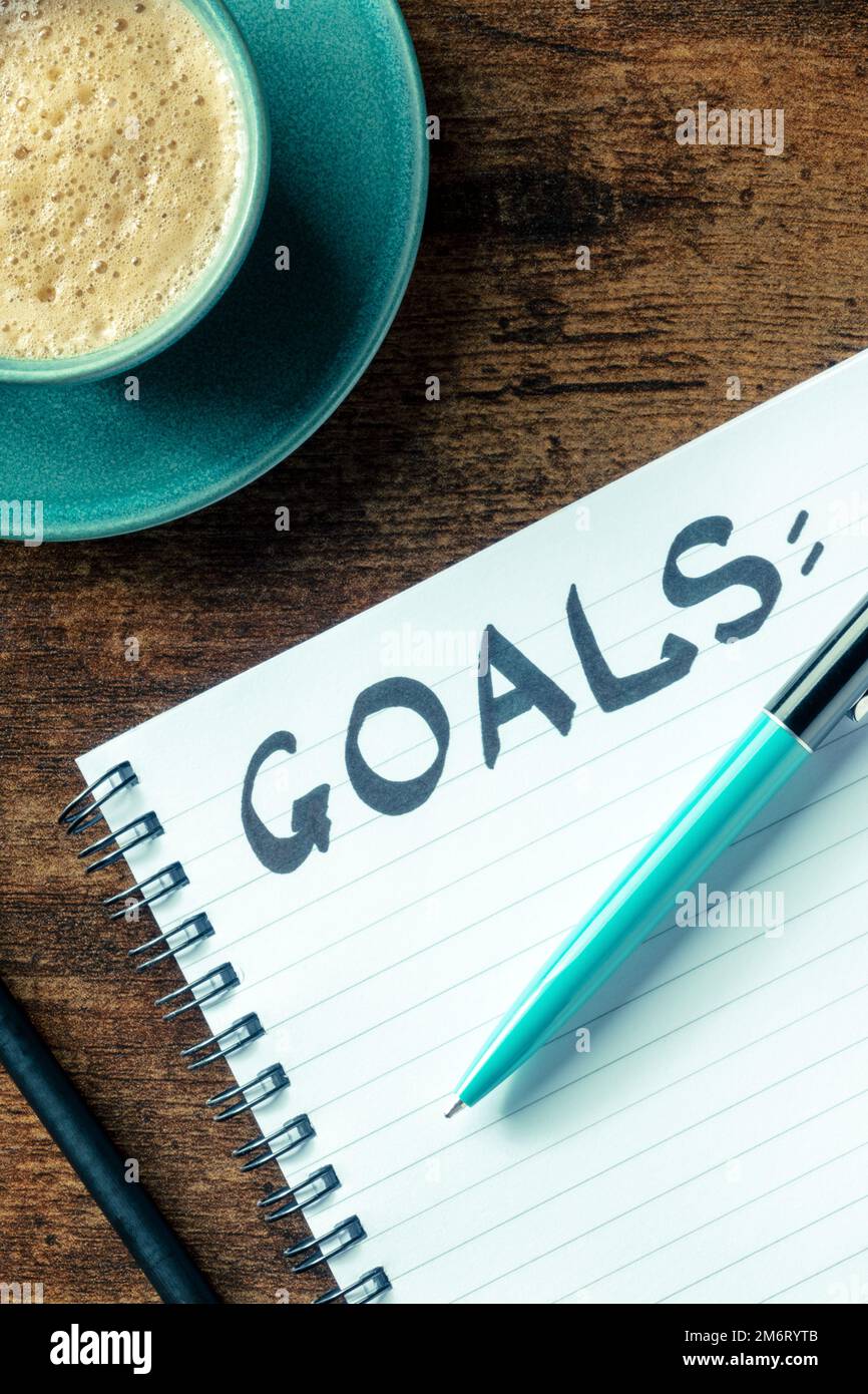 Goals, handwritten word in a notepad with a ballpoint pen and coffee ...