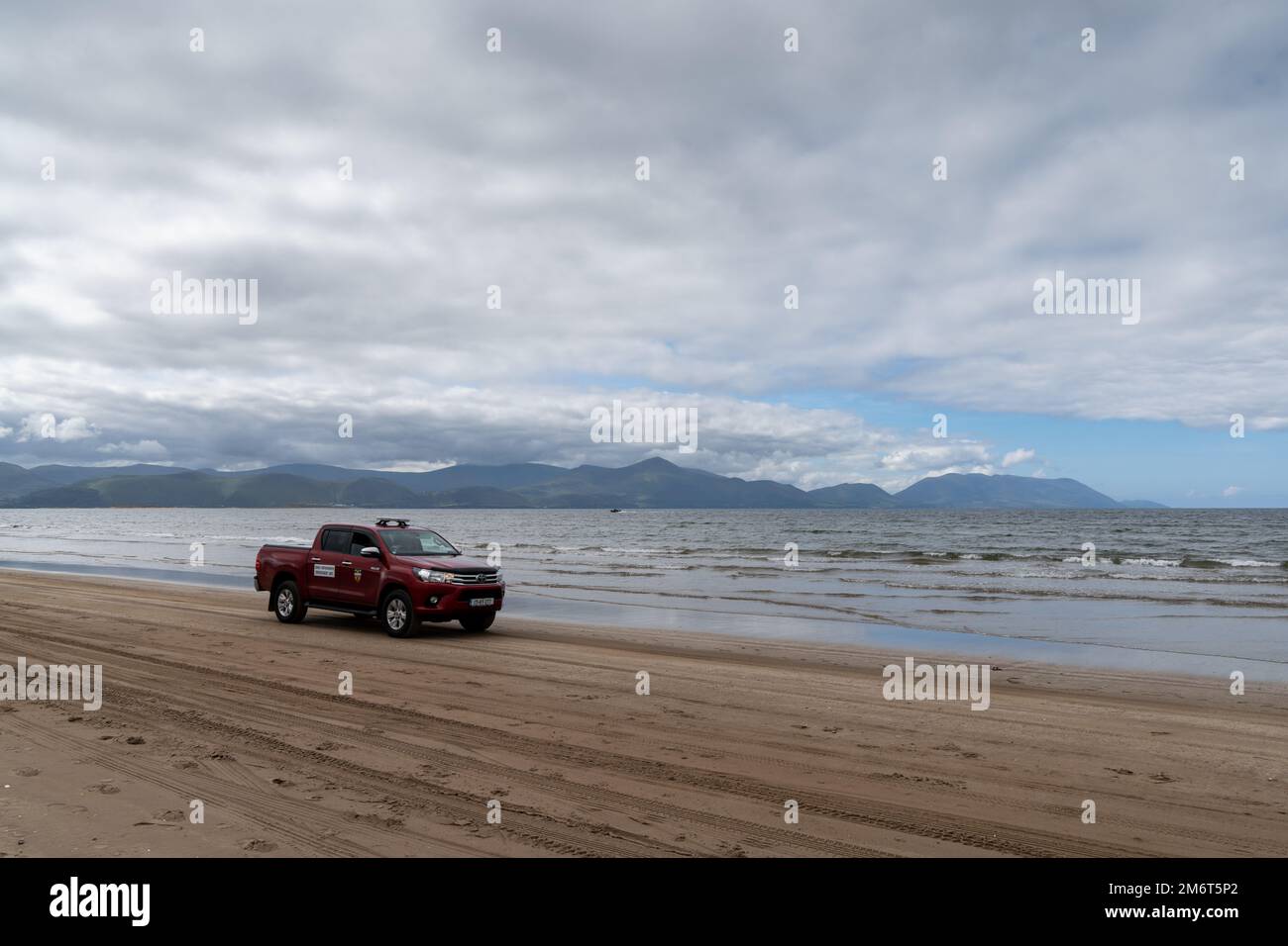 Red lifeguard pick-up truck driving on the beach at inch Strand in ...
