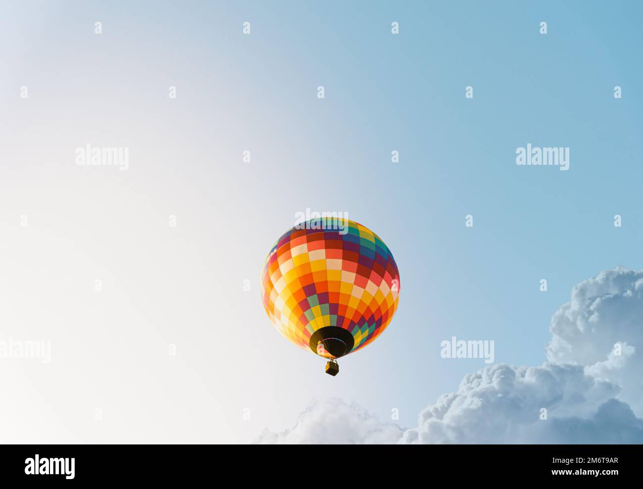 A low-angle shot of the colorful hot air ballon flying in the blue sky ...