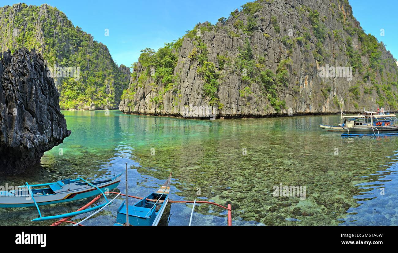 Coron Island Lagoon with local boats at the pier and an incoming touris ...