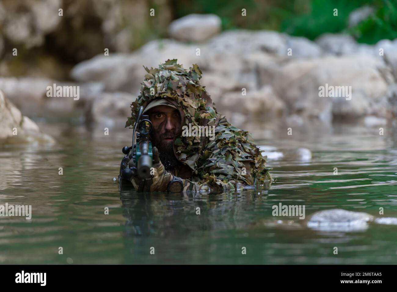 A military man or airsoft player in a camouflage suit sneaking the ...