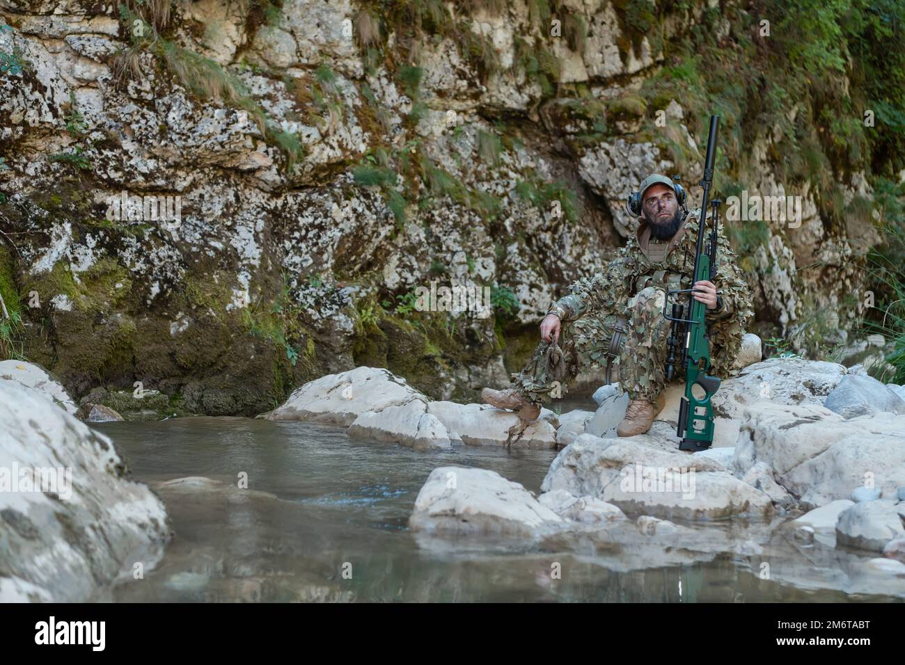 A military man or airsoft player in a camouflage suit sneaking the ...