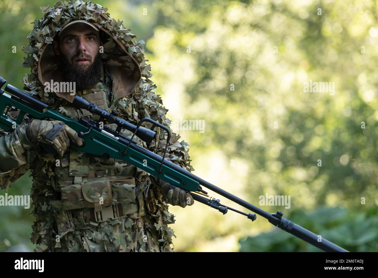 A military man or airsoft player in a camouflage suit sneaking the ...