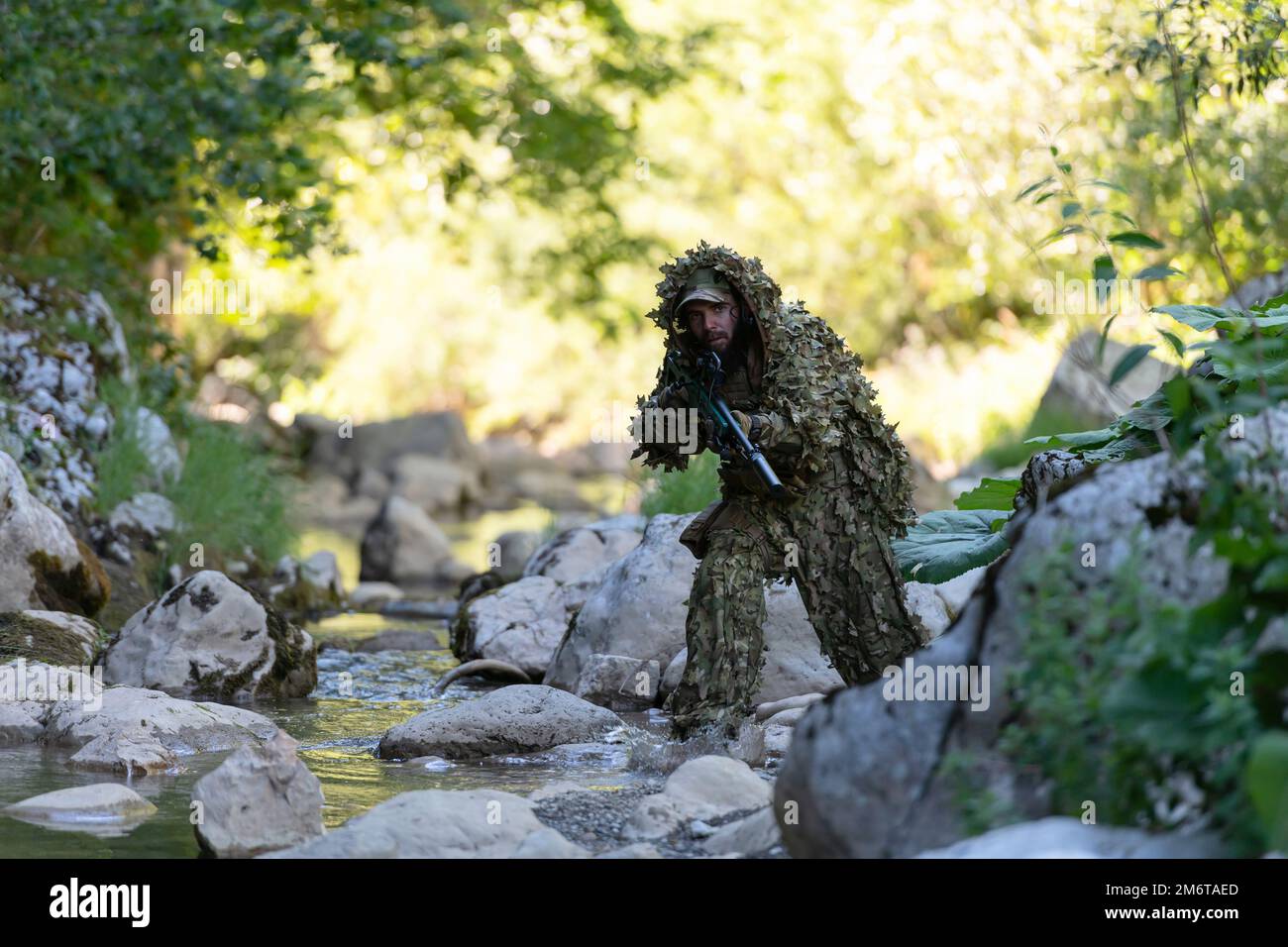 A military man or airsoft player in a camouflage suit sneaking the ...