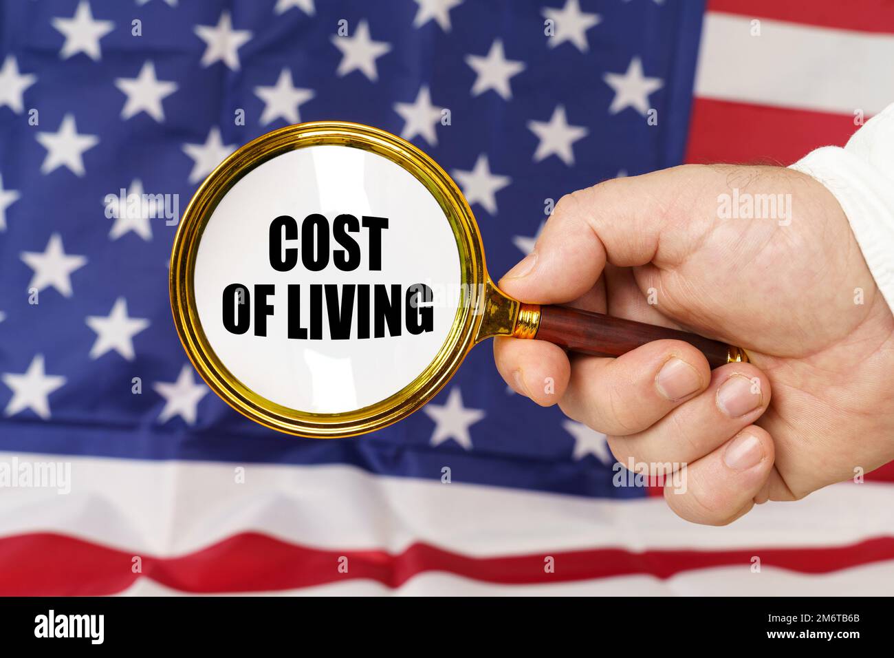In front of the American flag, a man holds a magnifying glass in his ...