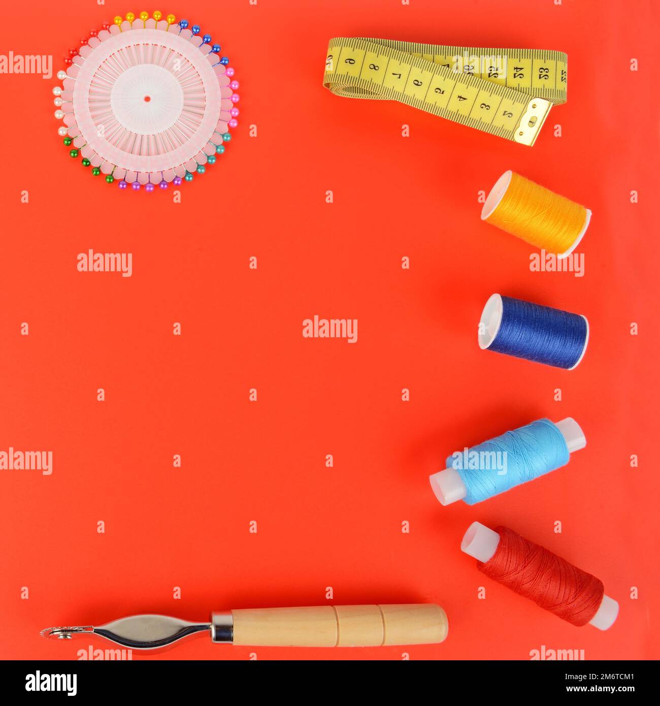 Composition with threads and sewing accessories on red background ...
