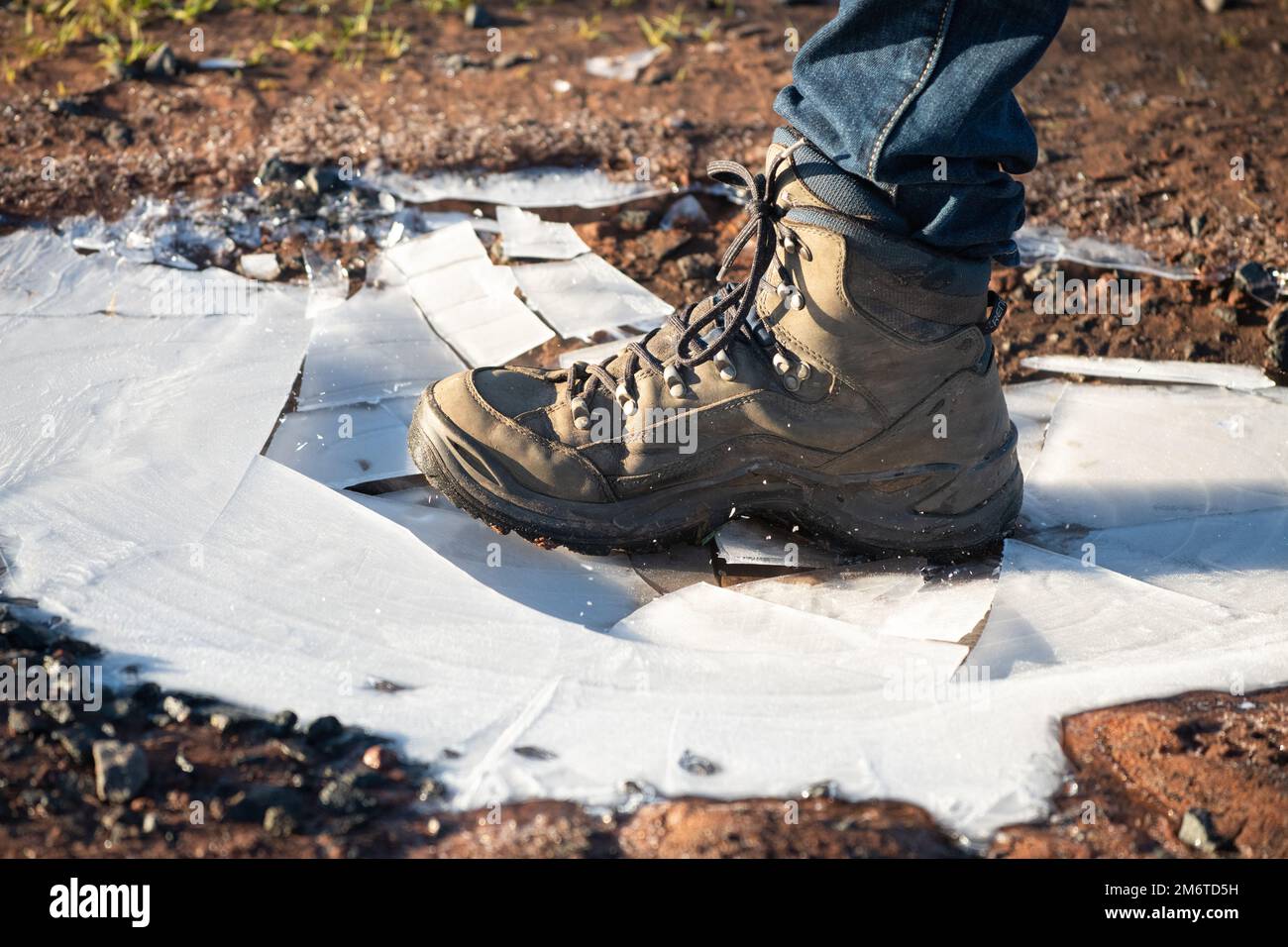 Breaking ice on frozen puddle Stock Photo - Alamy