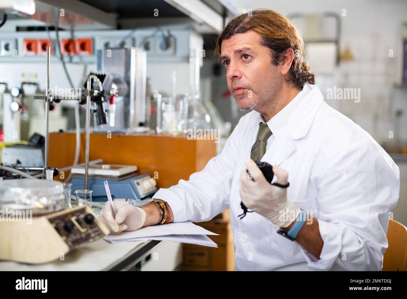 Male scientist engaged in research in chemical laboratory, noting ...