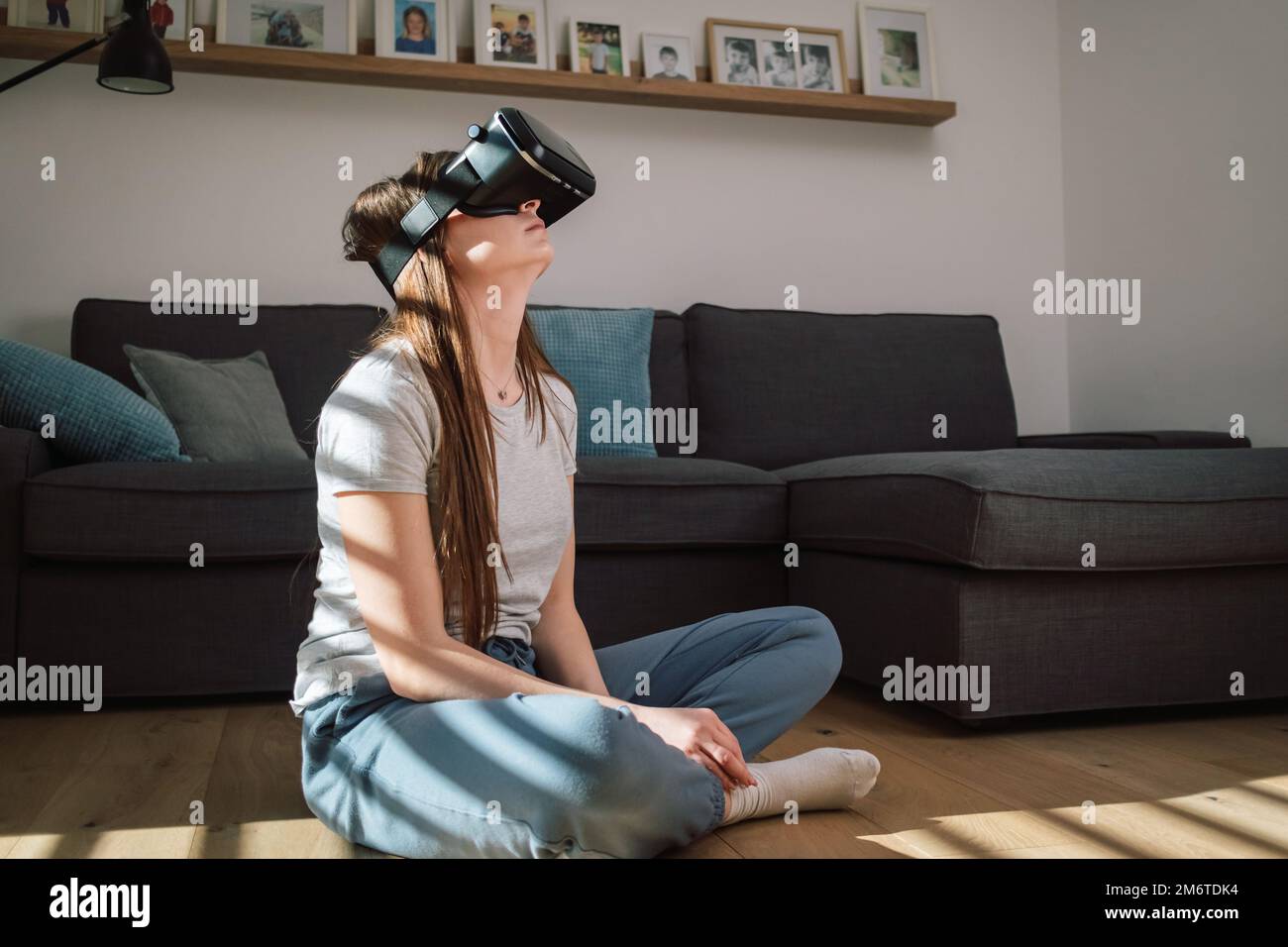 Young woman using virtual reality equipment, VR glasses, to look around ...
