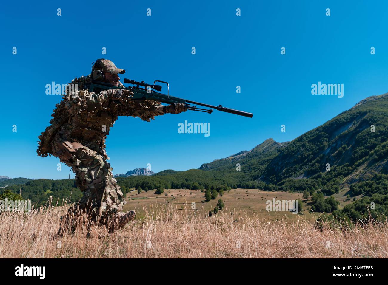 Army soldier holding sniper rifle with scope and aiming in forest. war ...