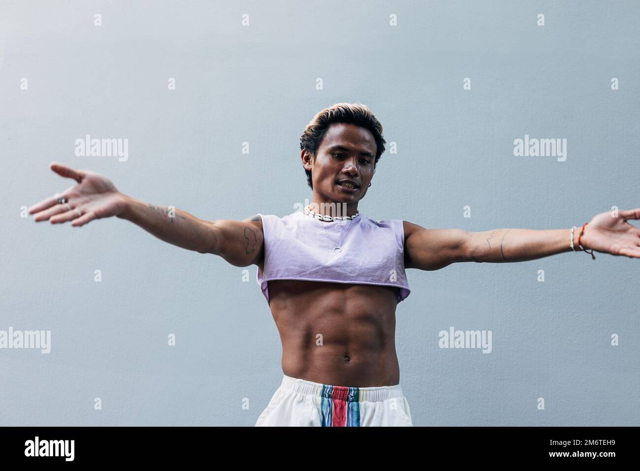 Muscular man in stylish clothes dancing at grey wall outdoors Stock ...