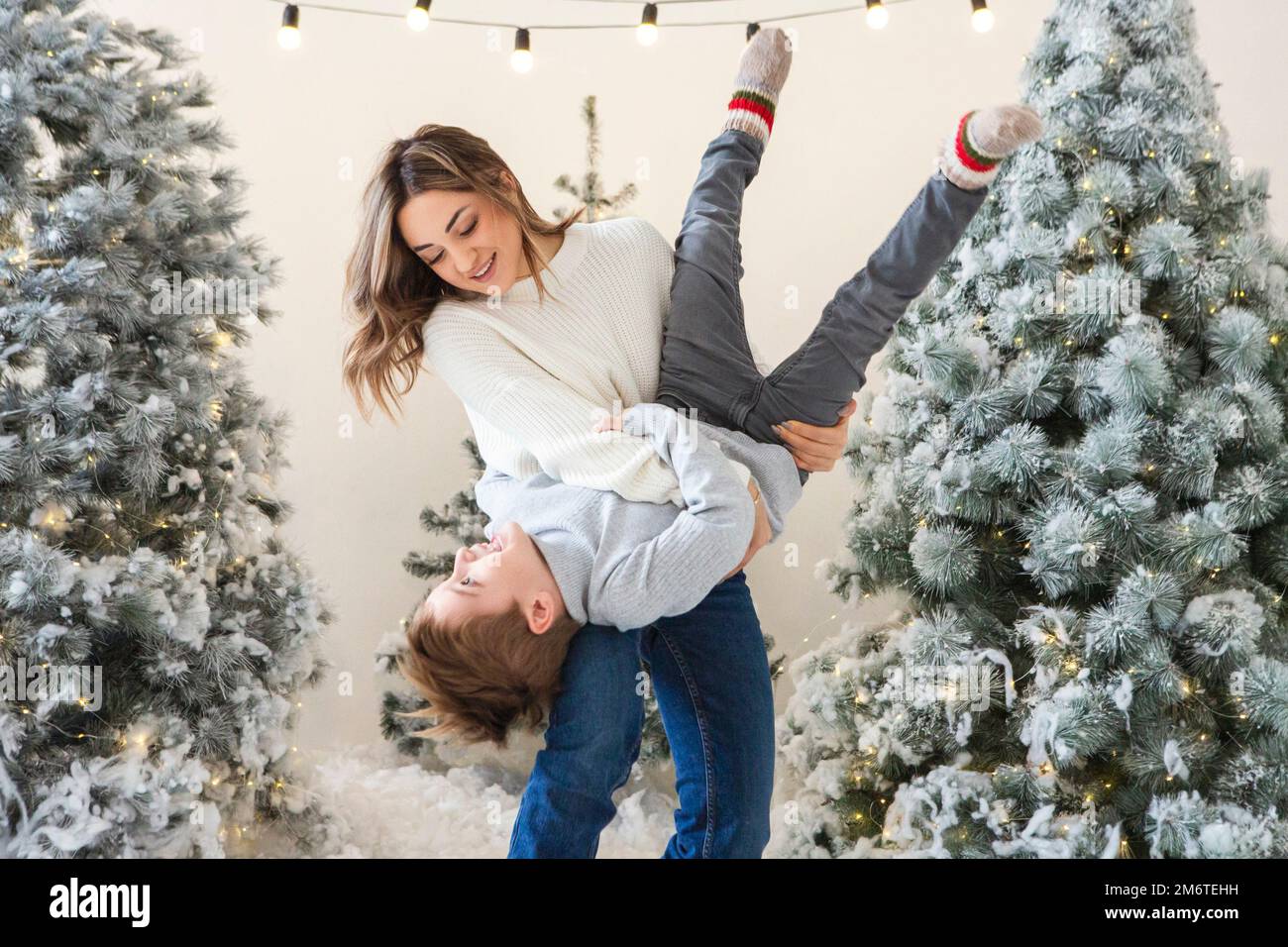 Positive young mother having fun with little boy son while standing ...