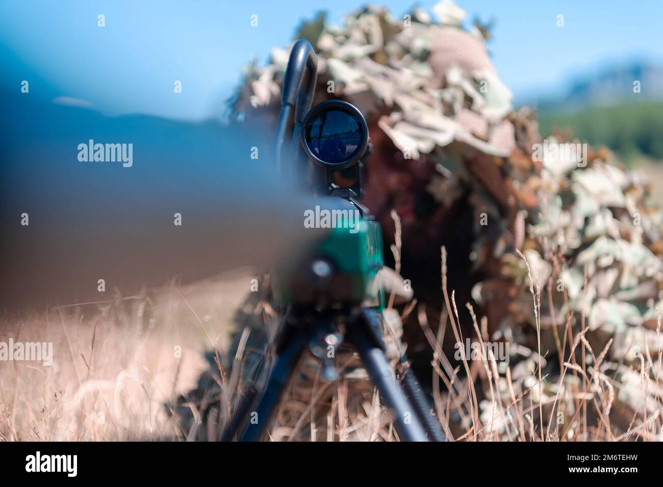 Army soldier holding sniper rifle with scope and aiming in forest. war ...
