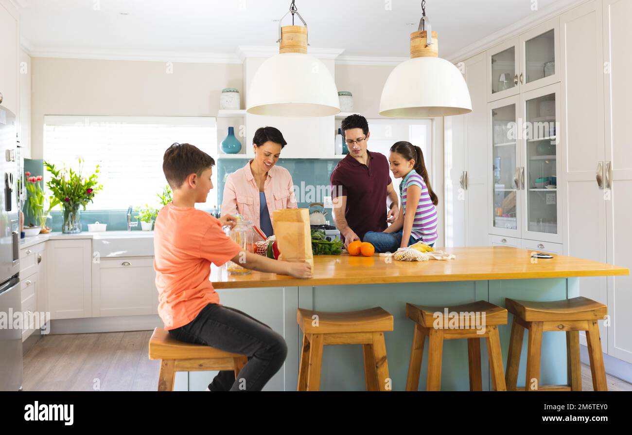 Caucasian family unpacking shopping bag together in the modern kitchen ...