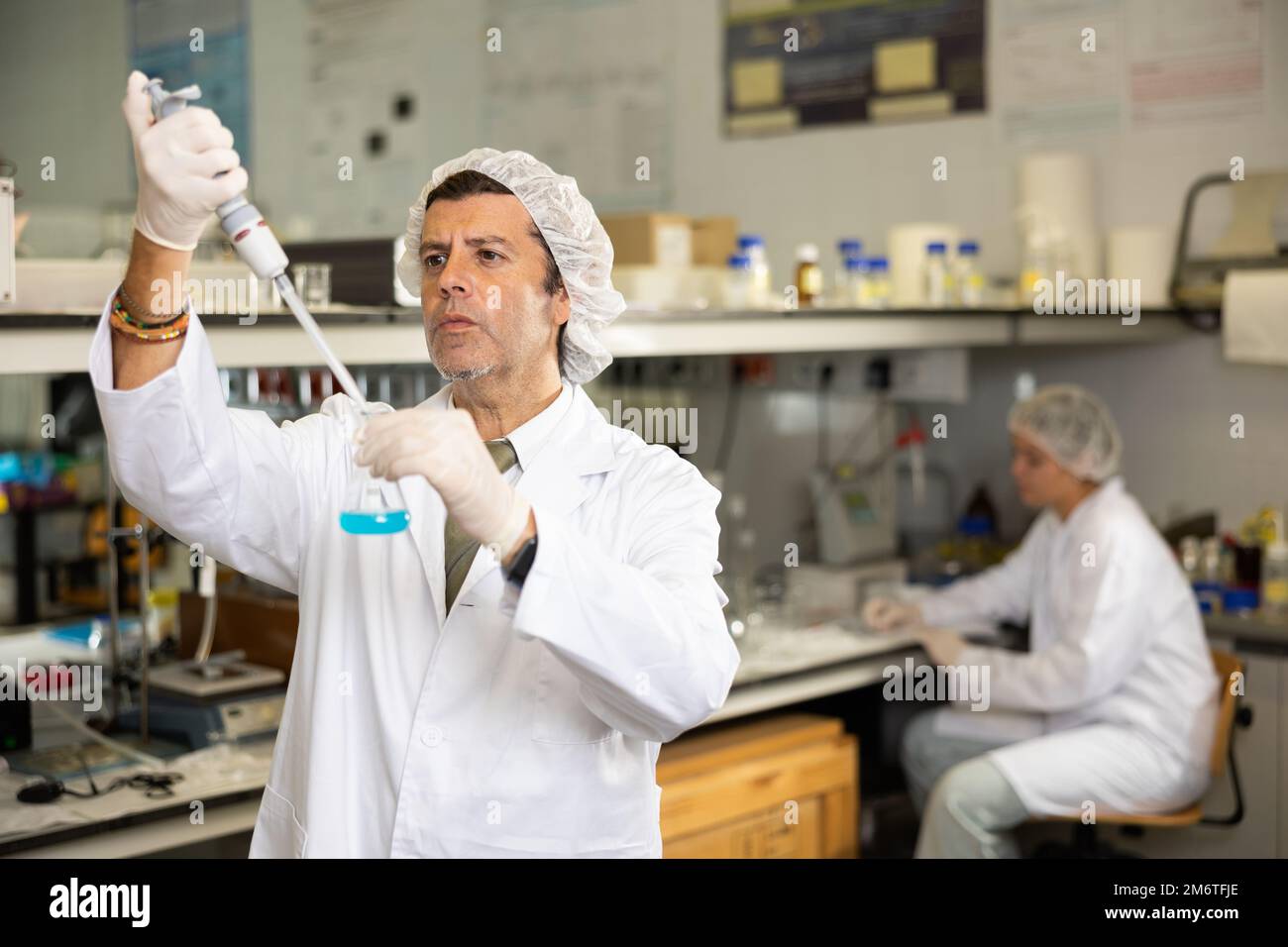 Concentrated Latin man biologist using mechanical lab pipette for ...
