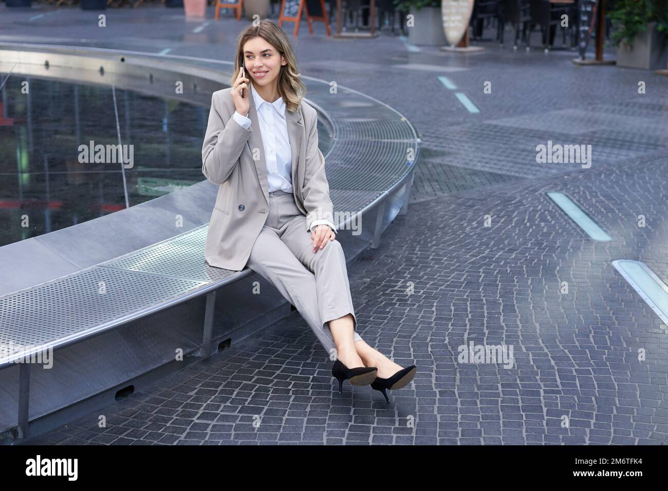 Young female manager. Corporate woman sitting outside on street and ...