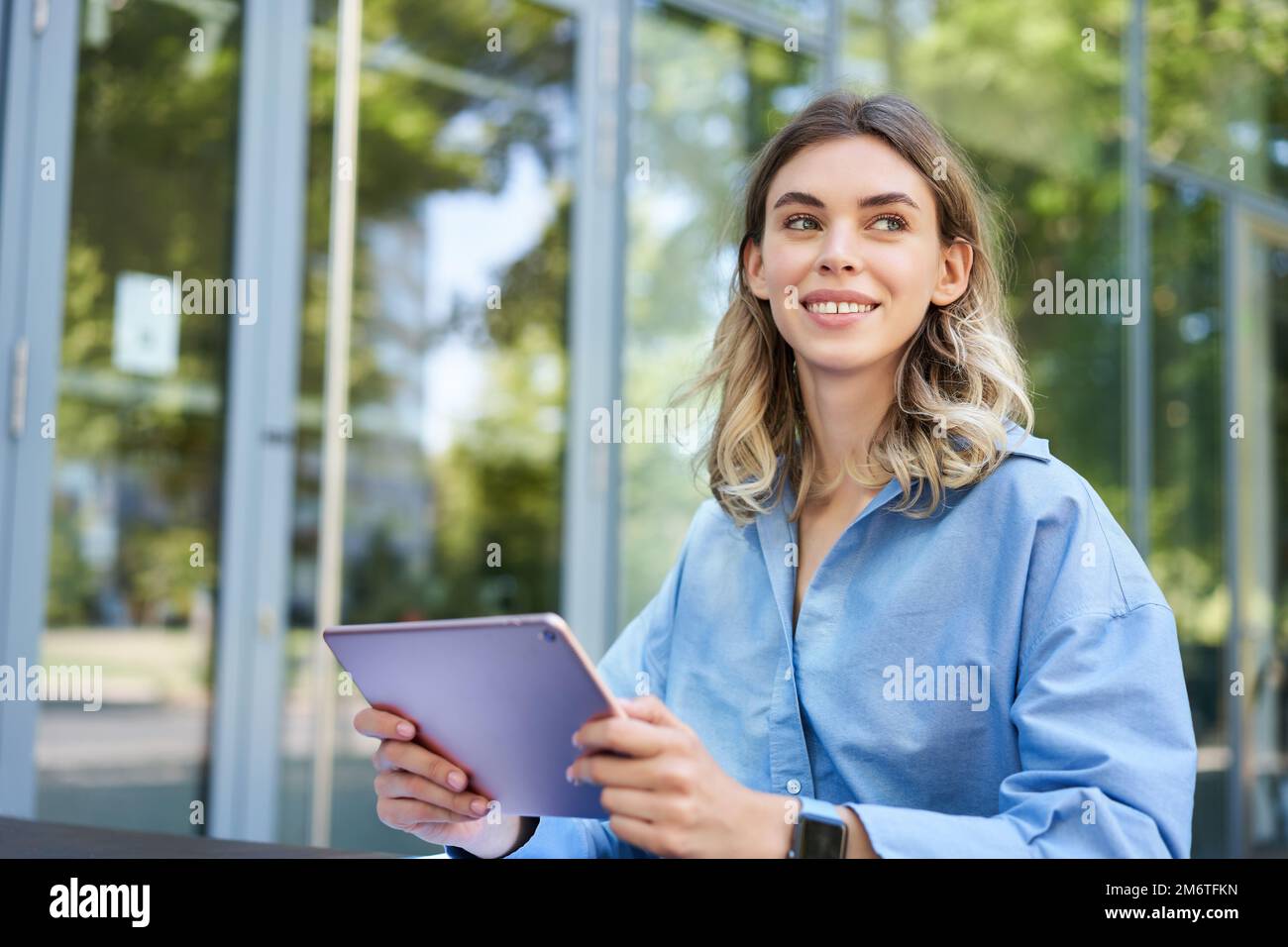Young digital nomad, woman with tablet, working outdoors on fresh air ...