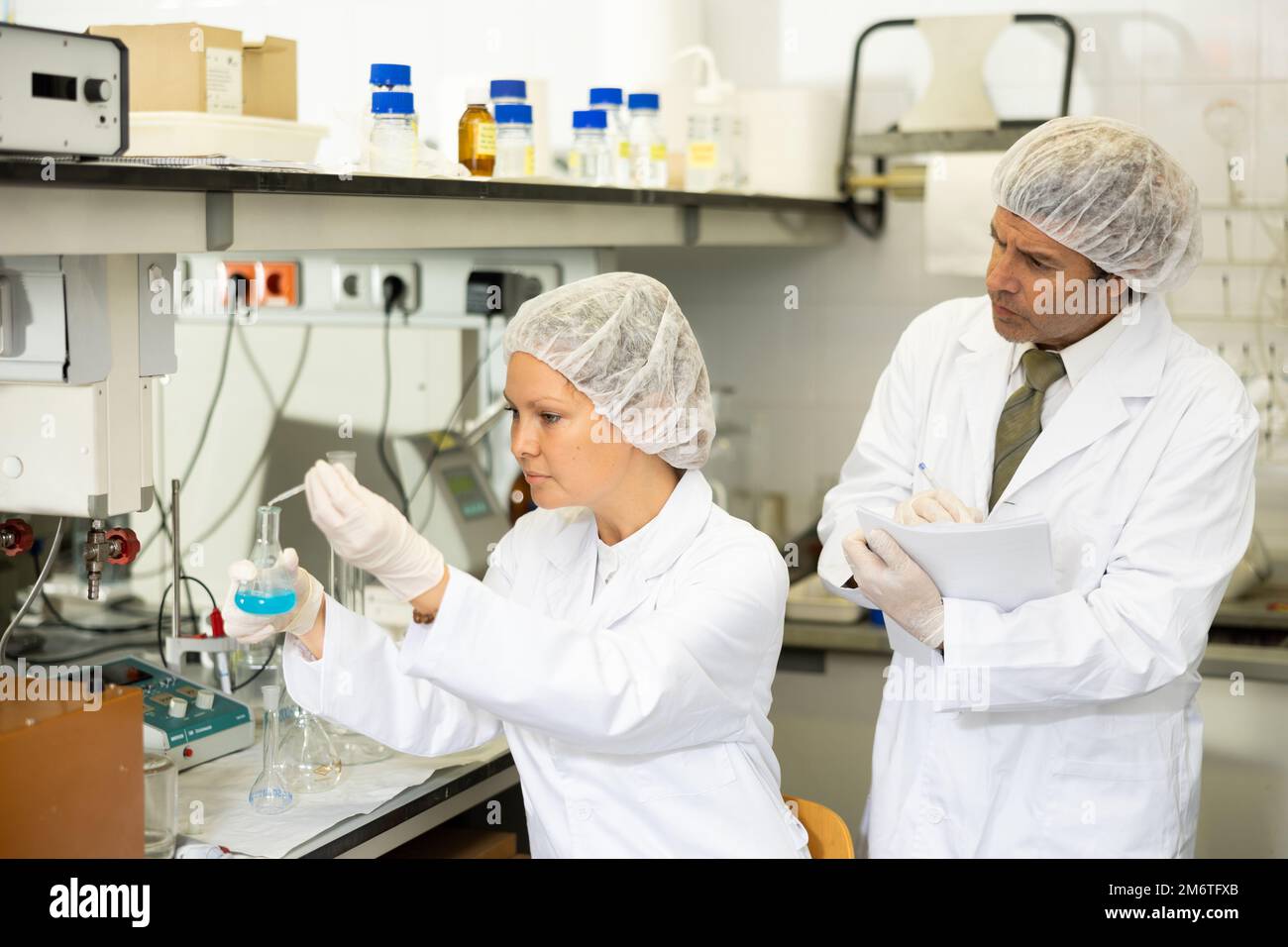 Middle-aged male and female researchers mixing reagents in test tube ...