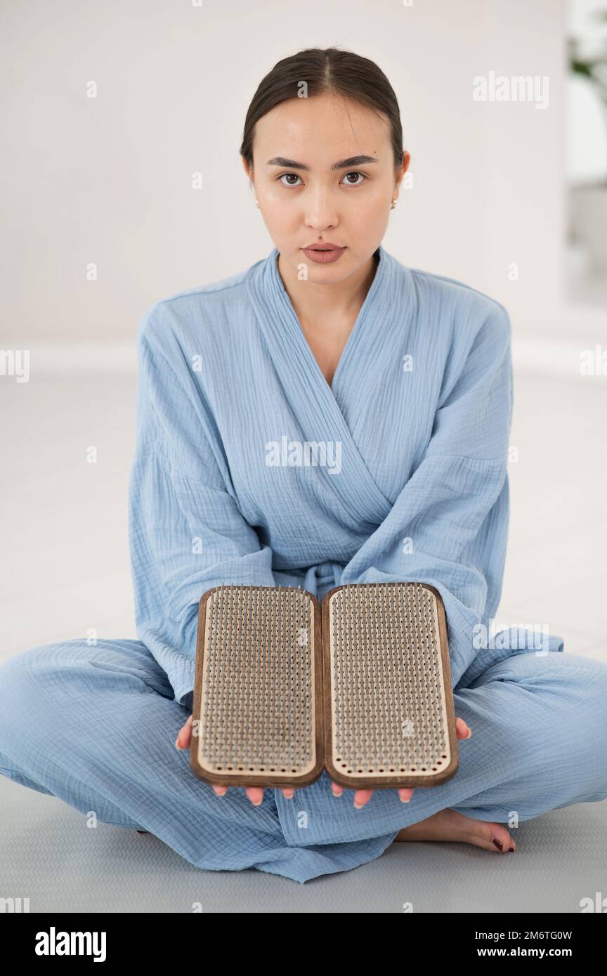 Asian Woman Sitting In Lotus Position On Yoga Mat And Holding Sadhu