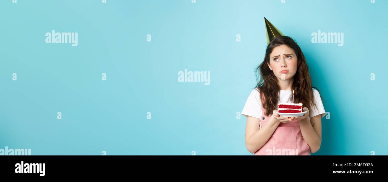 Holidays and celebration. Sad girl in party hat holding birthday cake ...