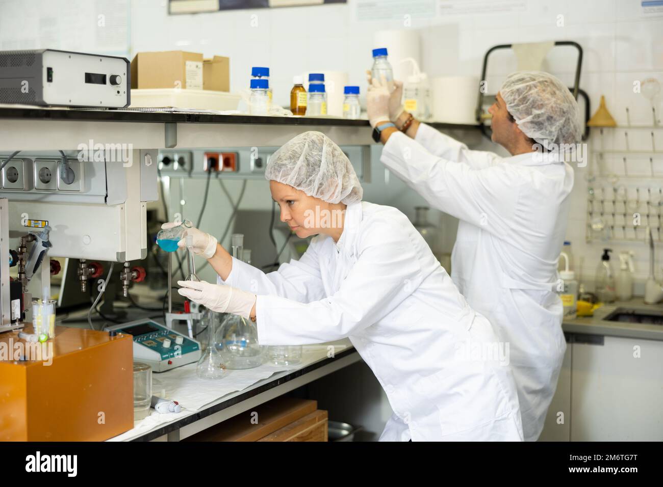 Professional male and female biologists in lab coat examining reaction ...