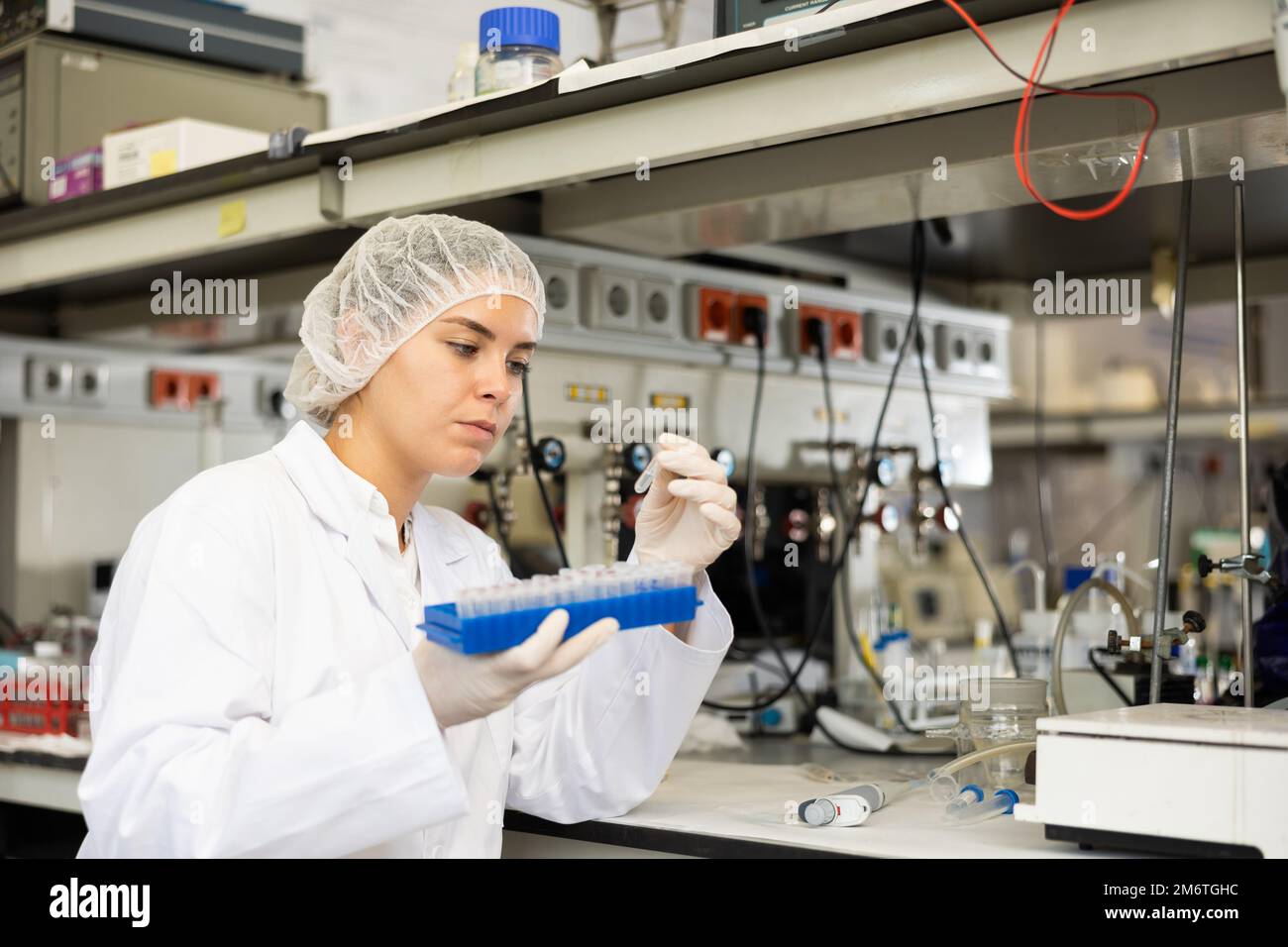 Efficient female lab technician working with reagents in test tubes ...