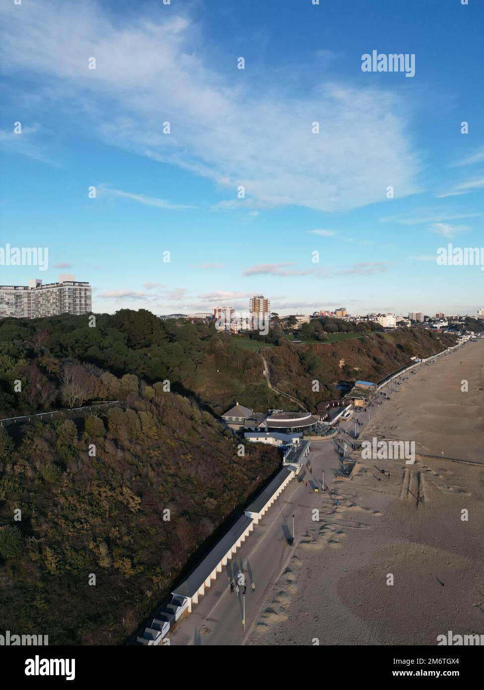 A vertical of hill covered with trees near a road, cloudy sky ...