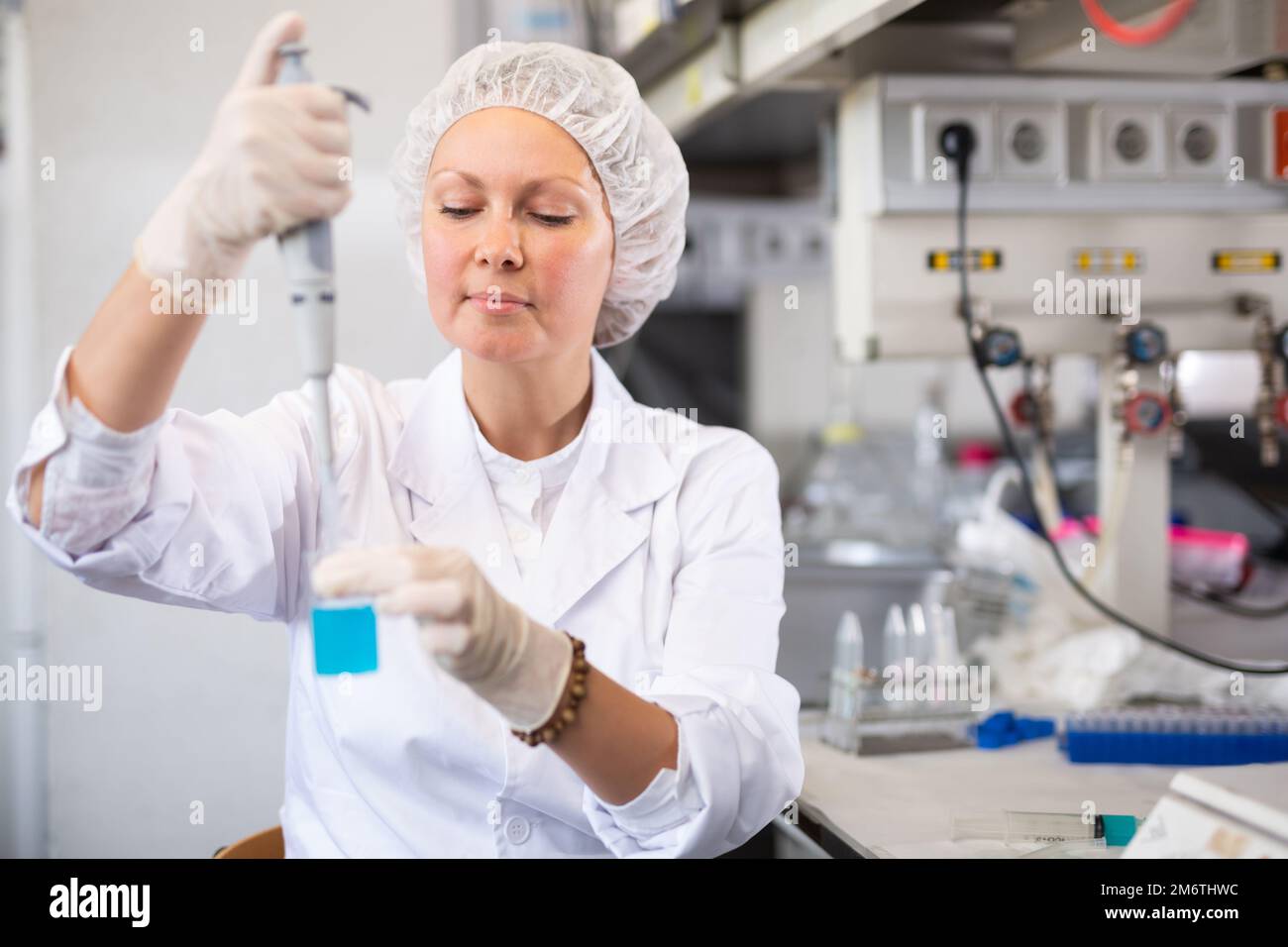 Efficient female lab technician working with reagents in test tubes ...