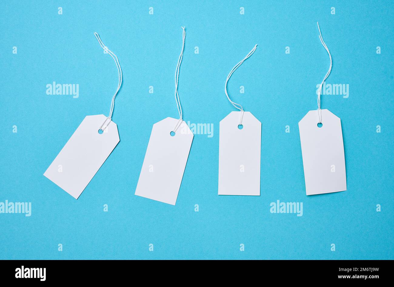Empty white cardboard tag on a white rope, blue background. Price tag ...