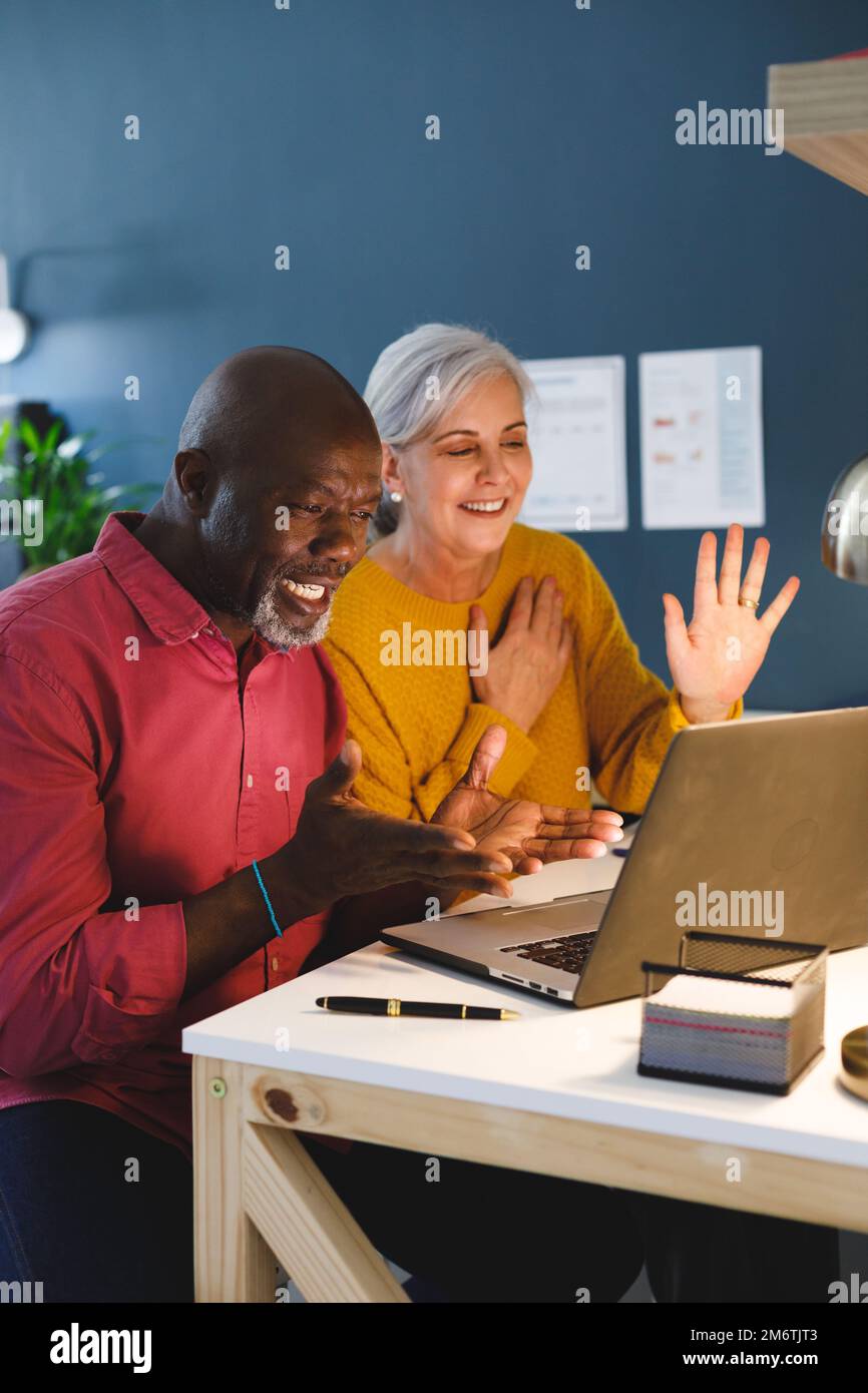 Senior diverse couple sitting at table and working Stock Photo - Alamy
