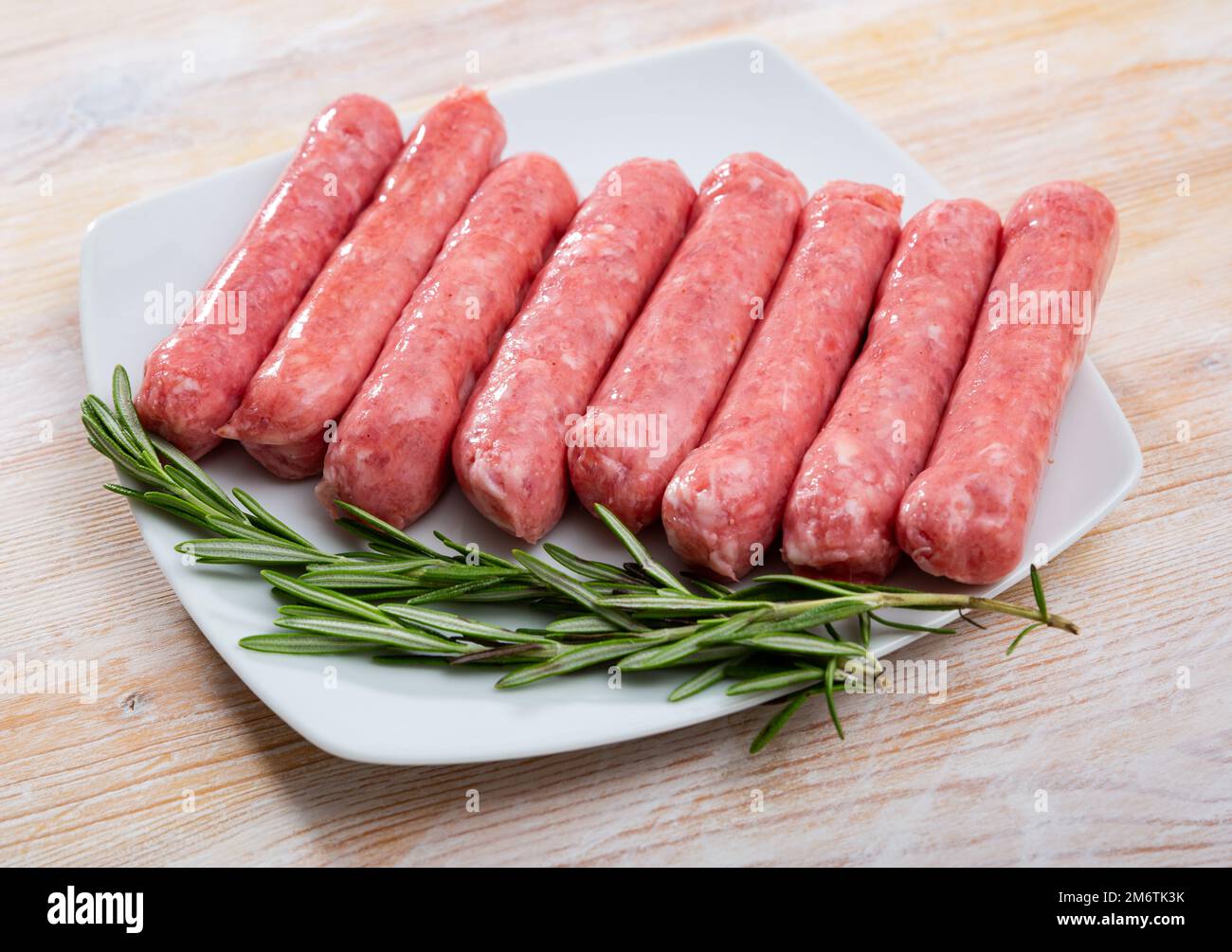 Raw farm sausages with rosemary on wooden table Stock Photo - Alamy