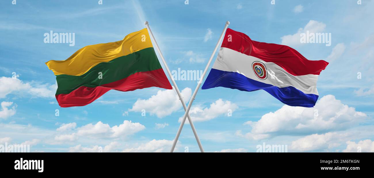 two crossed flags Paraguay and Lithuania waving in wind at cloudy sky ...