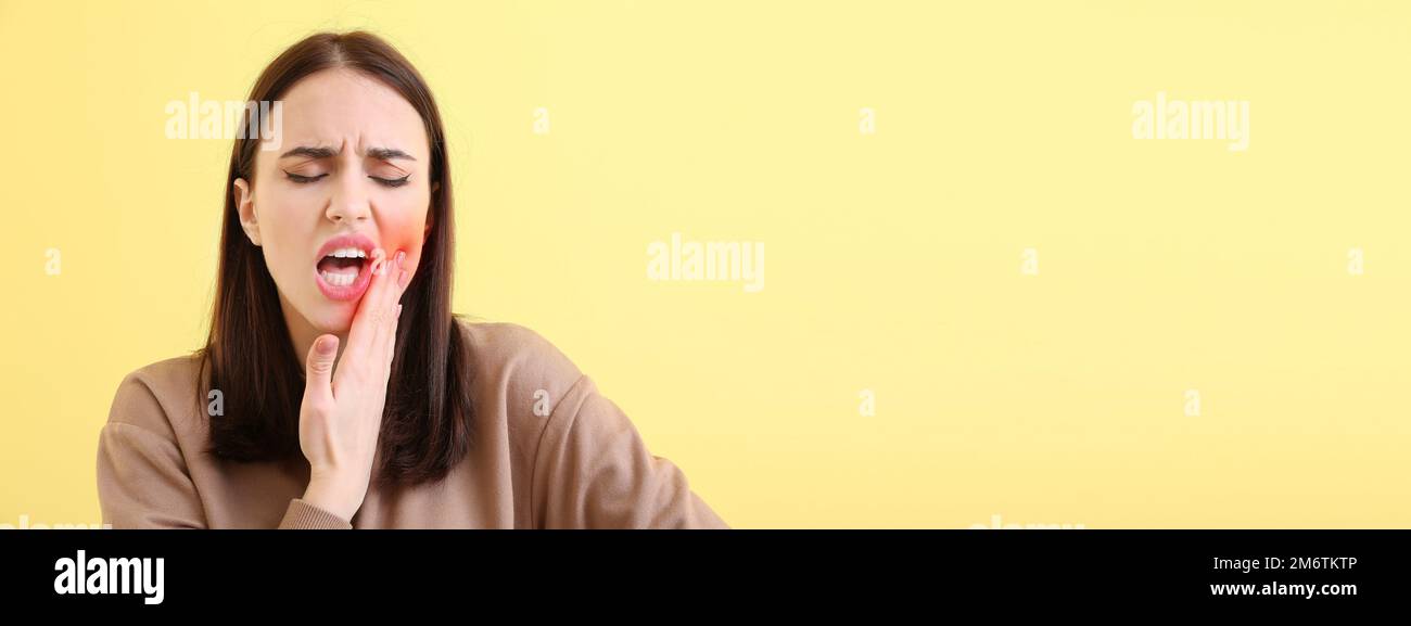 Young woman suffering from tooth ache on yellow background with space ...