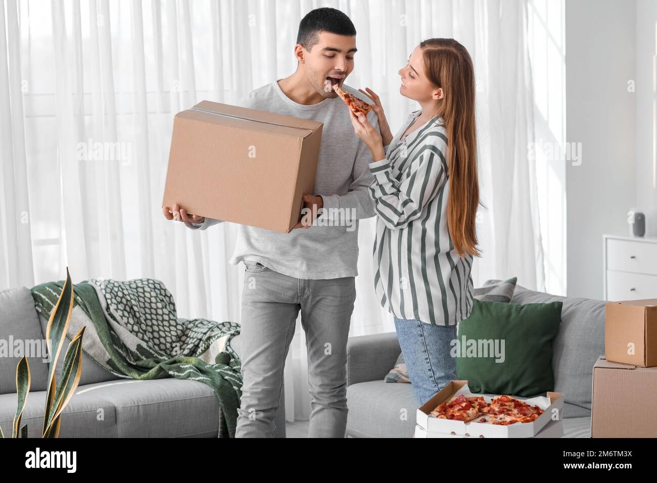 Happy young couple eating tasty pizza on moving day Stock Photo - Alamy