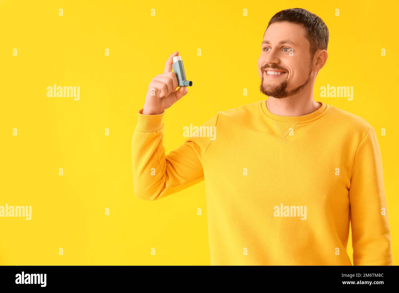 Man with inhaler on yellow background Stock Photo - Alamy