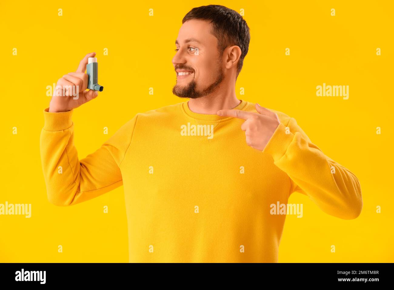 Man with inhaler on yellow background Stock Photo - Alamy