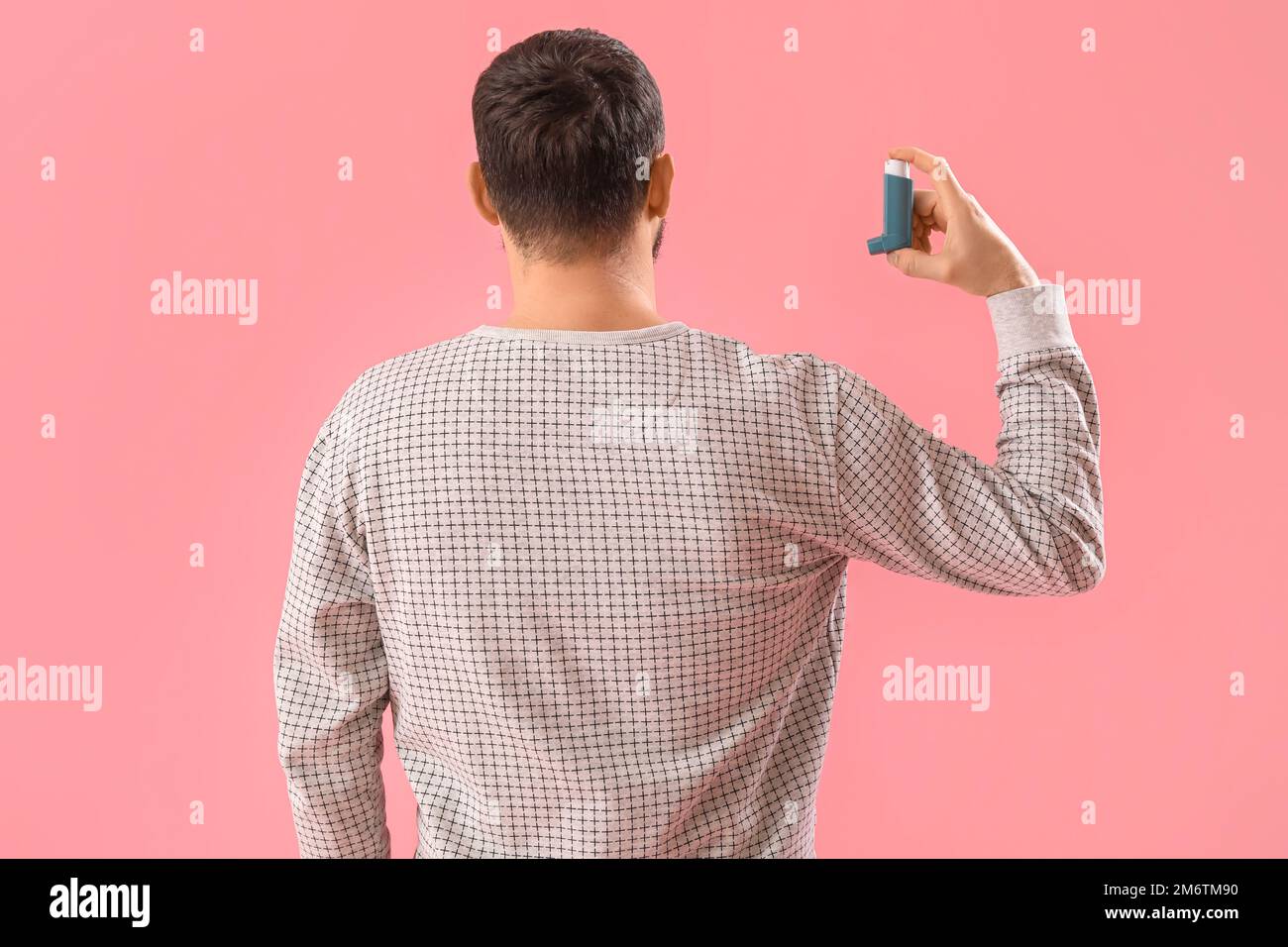 Man with inhaler on pink background, back view Stock Photo - Alamy