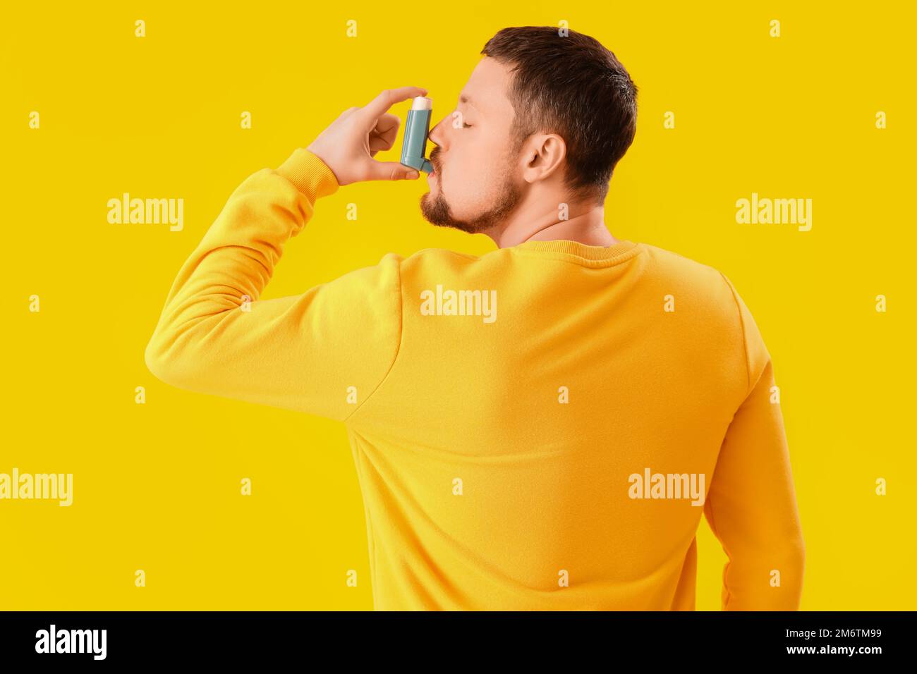 Sick man with inhaler on yellow background Stock Photo - Alamy