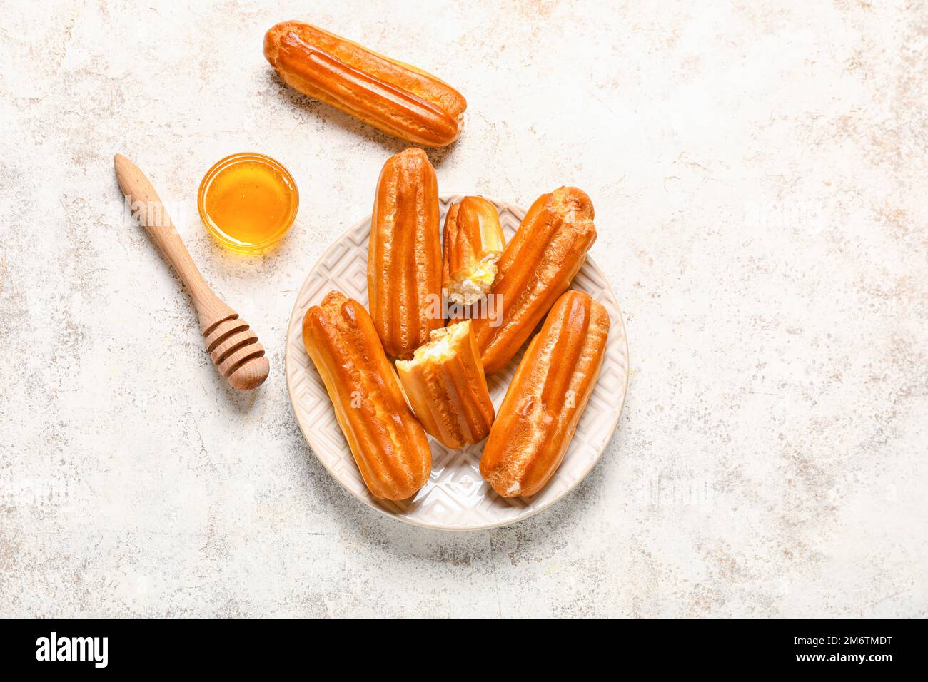 Plate with tasty eclairs and honey on light background Stock Photo - Alamy