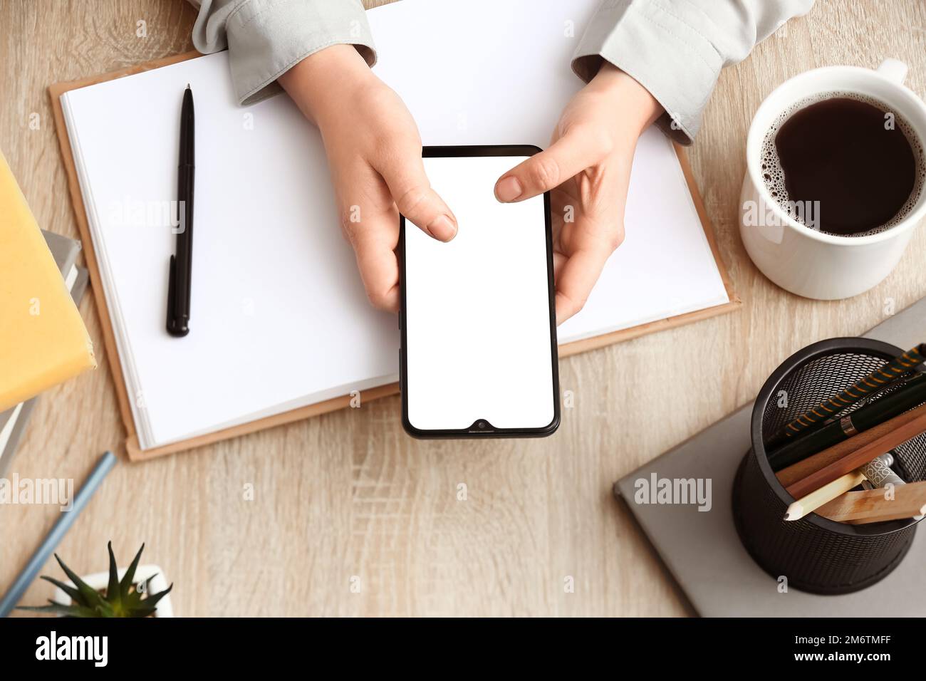 Female hands with modern mobile phone, notebook and cup of coffee on ...