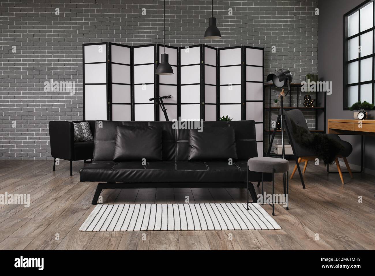 Interior of stylish office with black couch, workplace and folding ...
